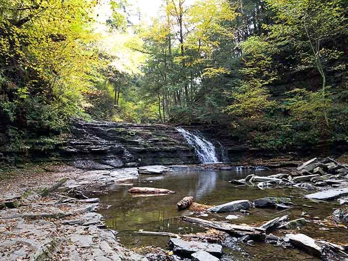 Nature's perfect postcard moment: a gentle waterfall cascades over ancient rock formations, creating the kind of tranquility you can actually hear.