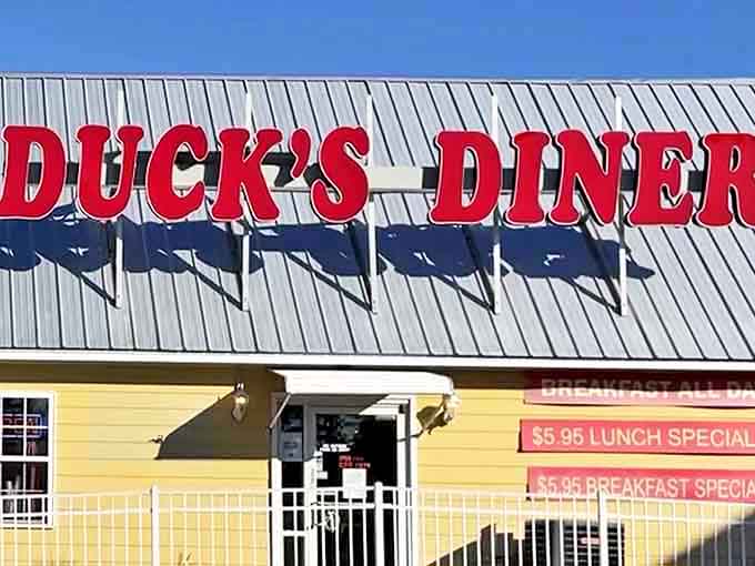 The sunshine-yellow exterior of Duck's Diner stands like a beacon of breakfast hope, complete with its cartoon mascot promising good times and better pancakes.