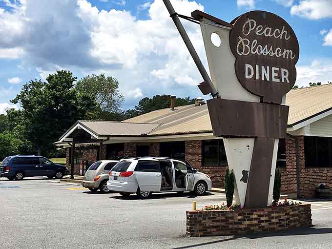 The iconic Peach Blossom sign stands like a retro beacon, promising comfort food salvation to hungry Spartanburg travelers since 1958.