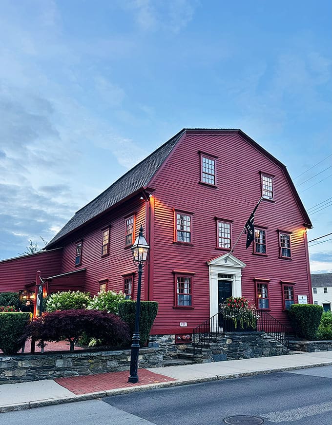 The crimson colonial beauty stands proudly against the twilight sky, like a time machine disguised as New England architecture.