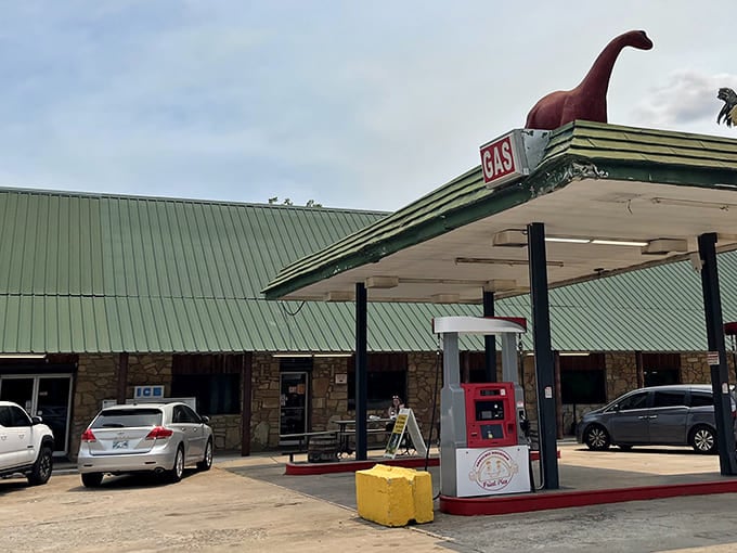 A quirky dinosaur figure tops the vintage gas station canopy, a whimsical landmark guiding hungry travelers to fried pie paradise.