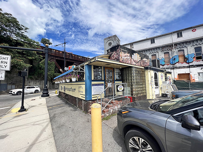 The classic blue-trimmed exterior of Miss Worcester Diner sits proudly beneath railroad tracks, a time capsule of Americana waiting to serve up breakfast dreams.