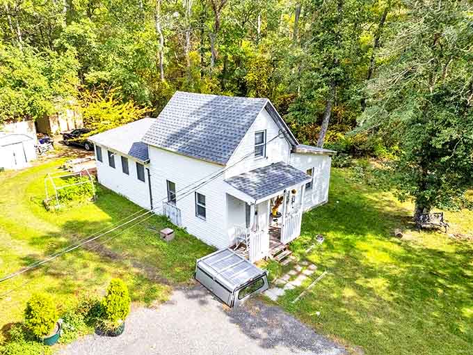 Classic white farmhouse nestled among trees &ndash; affordable charm that whispers "welcome home" without breaking the bank.