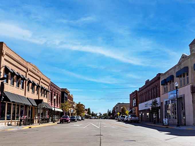 Sunlight bathes these century-old storefronts in golden warmth, while awnings create pockets of shade perfect for window shopping or spontaneous conversations.