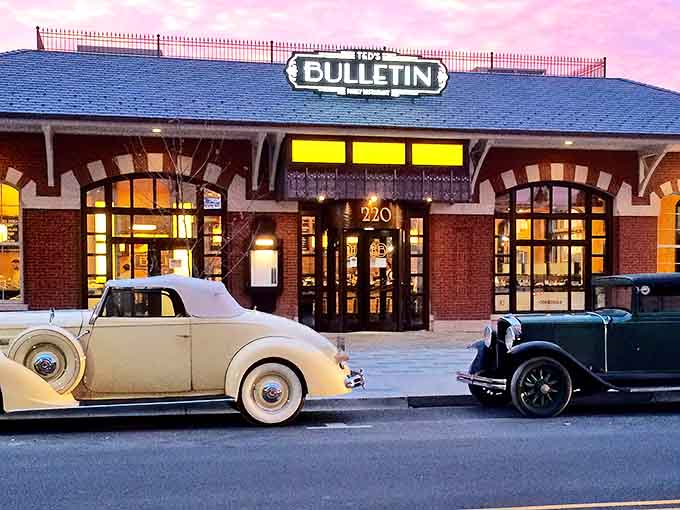 Ted's Bulletin's brick fa&ccedil;ade glows at dusk, with vintage cars parked outside like a scene from a nostalgic dream where comfort food reigns supreme.