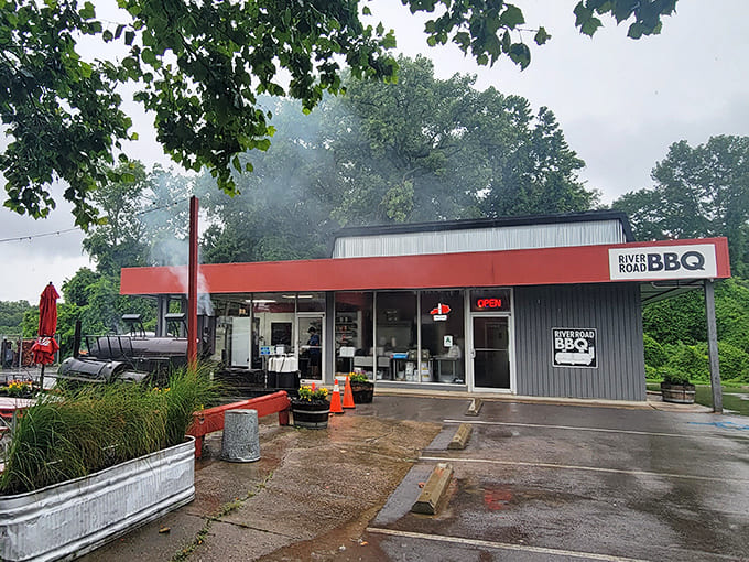 Wisps of smoke drift skyward from River Road BBQ's smokers, promising slow-cooked perfection in Louisville's lush surroundings.