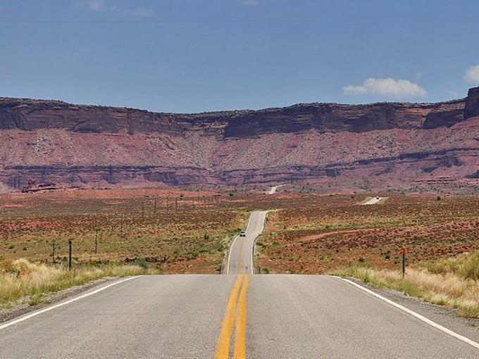 The highway stretches toward distant mesas like an invitation to adventure. No RSVP required&mdash;just a full tank of gas.