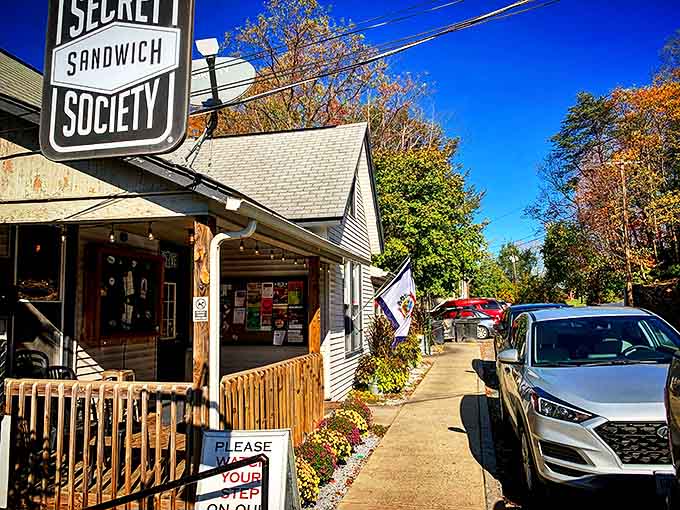 The charming cottage exterior of Secret Sandwich Society stands like a culinary lighthouse amid Fayetteville's autumn splendor, beckoning hungry travelers with promises of sandwich nirvana.