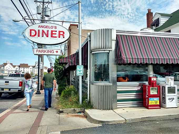 That iconic oval sign beckons like a lighthouse for hungry travelers. Angelo's stainless steel exterior and striped awnings are a portal to simpler, delicious times.
