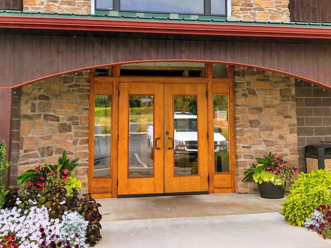 The welcoming entrance to Traditions Restaurant & Bakery, where wooden doors and stone walls promise comfort before you've even stepped inside. Those colorful planters aren't just for show&mdash;they're the first hint that attention to detail matters here.