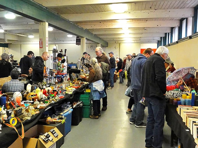 A treasure hunter's paradise in action &ndash; colorful handcrafted suncatchers dangle in the foreground while flannel-clad bargain seekers huddle around tables of potential finds, each on their own quest for that perfect something.