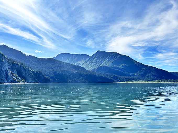 The tranquil waters of Kachemak Bay mirror towering mountains, where silence speaks louder than words in this Alaskan paradise.