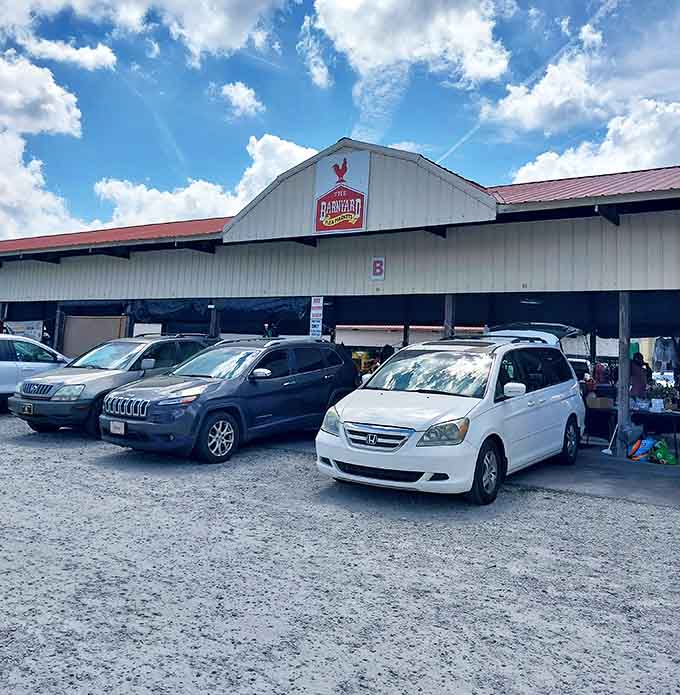 The iconic white barn structure of The Barnyard Flea Markets stands proudly against a blue Georgia sky, promising treasures within for those brave enough to hunt.