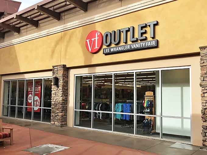The VF Outlet beckons with colorful apparel promises behind gleaming glass doors. Desert shopping at its most tempting.