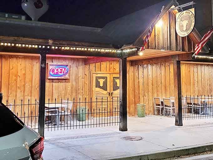 Nighttime transforms this wooden facade into a warm, glowing invitation. Those neon "OPEN" letters might as well say "Come on in, we've been expecting you."
