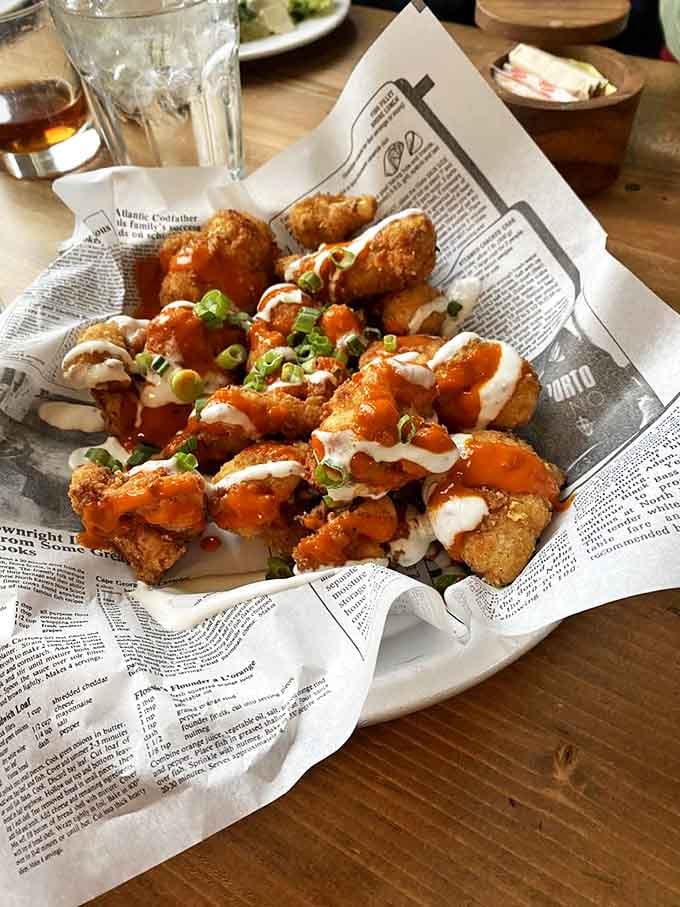 Buffalo cauliflower that might just convert carnivores. Crispy, saucy, and served on newspaper&mdash;street food sophistication with a vegetable twist.
