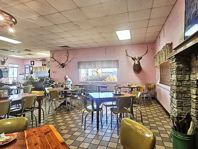 The stone fireplace centerpiece says "cozy cabin," while the mounted deer heads say "we know our way around local game."