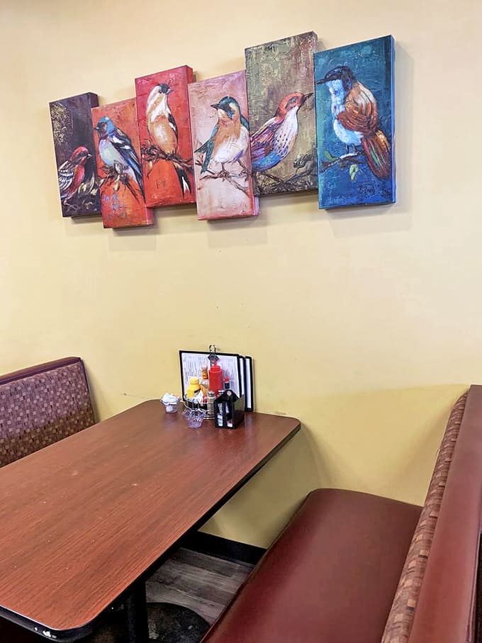 Colorful bird artwork watches over diners like cheerful guardians, adding splashes of whimsy to conversations about weather, crops, and local gossip.