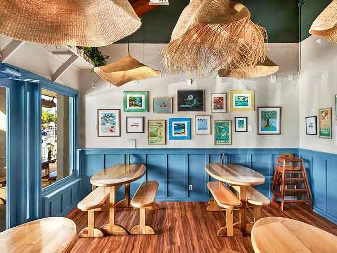 Surfboard-shaped tables under woven light fixtures create the perfect balance of island charm and practical dining. Beach vibes without the sand in your shorts.