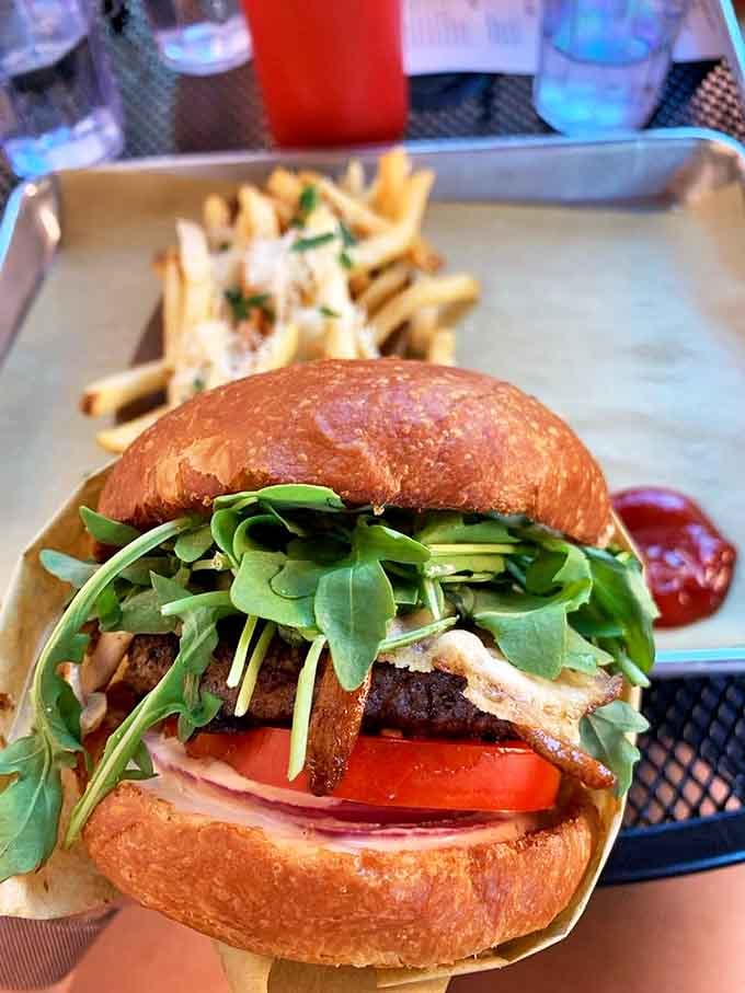 A burger so photogenic it deserves its own headshot &ndash; layers of fresh ingredients stacked with architectural precision on a golden brioche throne.