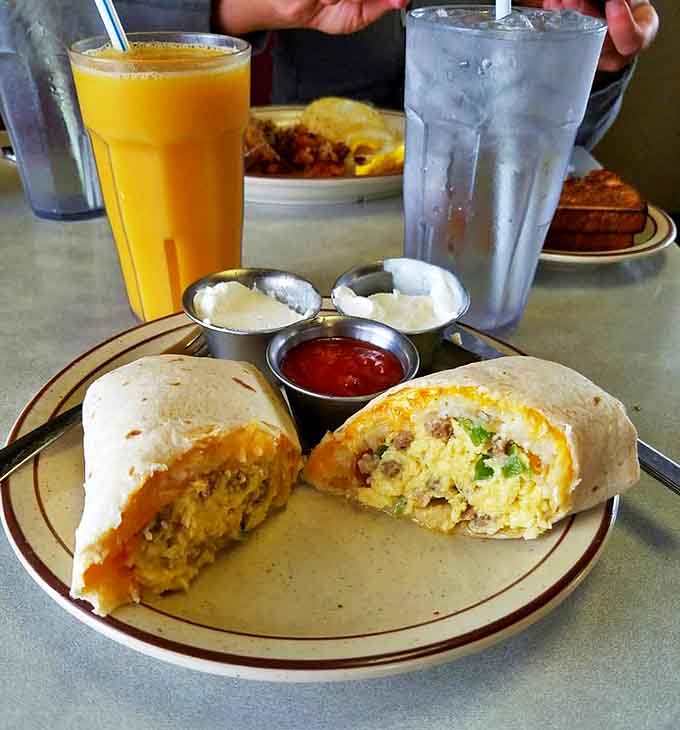Breakfast burritos: where morning meets Mexico in a handheld package. The orange juice stands by, ready to cut through all that savory goodness.