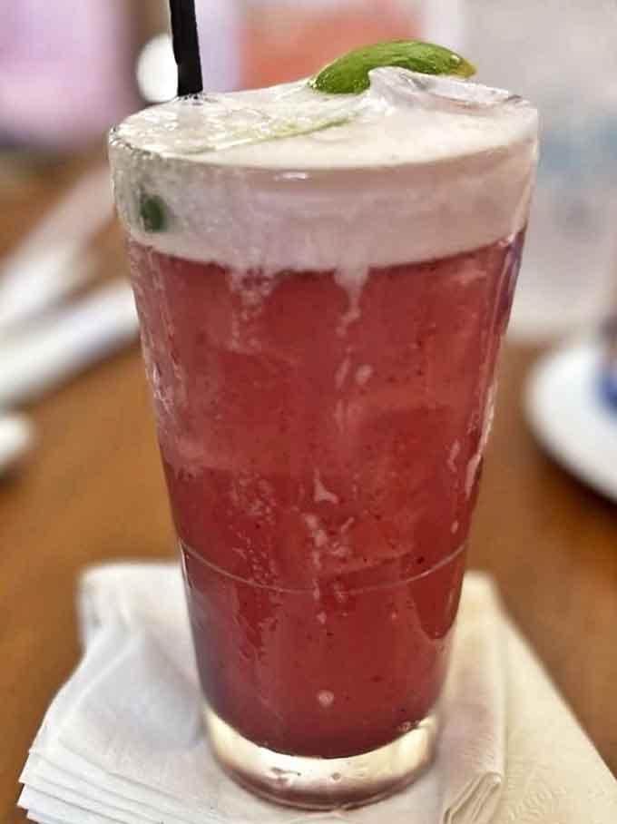 Ruby-red refreshment topped with a frothy crown and lime garnish &ndash; the kind of drink that makes you forget checking your phone for hours.