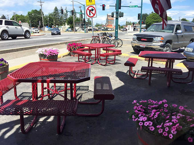 Summer dining at its finest: red picnic tables adorned with flower pots create an outdoor oasis where burgers taste even better under Idaho's big sky.