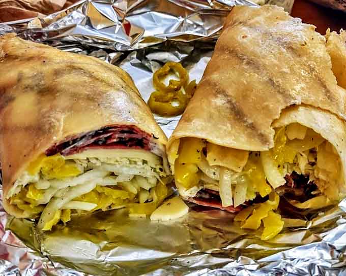 Wrapped in foil like the precious gift it is, this pastrami sandwich glistens with promise and pickle spears.