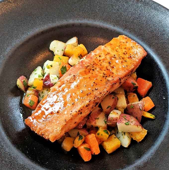 This salmon doesn't just sit on vegetables—it presides over them, glistening with the confidence of perfectly cooked fish.