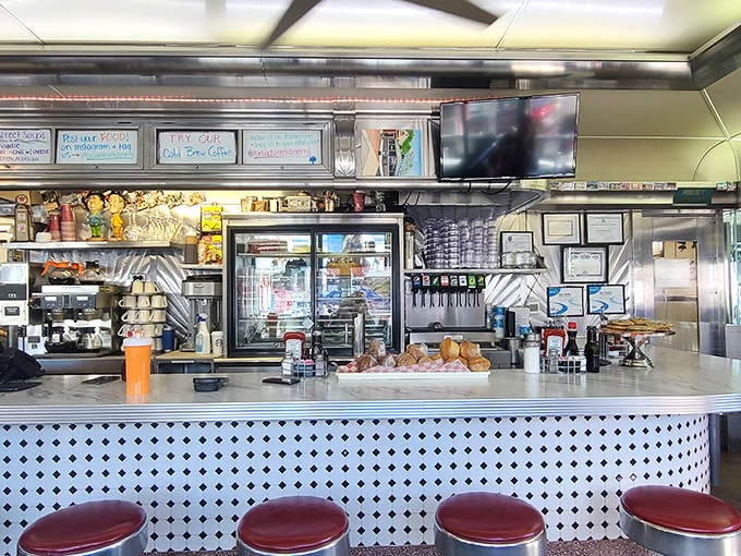 The counter offers front-row seats to the culinary show. Gleaming surfaces, organized chaos, and the promise of coffee refills without asking.