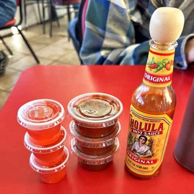 The holy trinity of diner condiments &ndash; where Cholula hot sauce stands guard over the jam and salsa reserves for emergency flavor deployment.