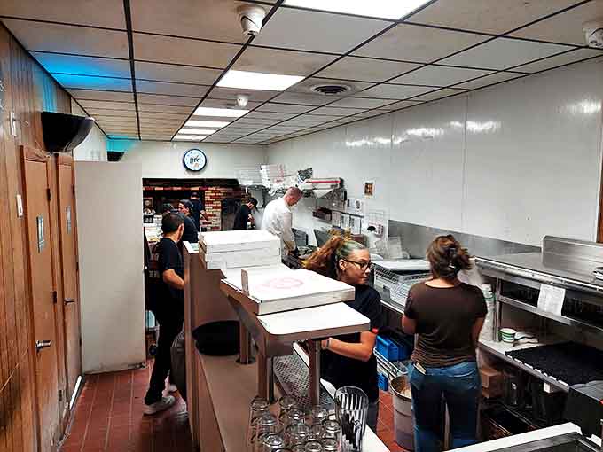 The kitchen at Sally's&mdash;where pizza alchemy happens daily. Less "open concept" and more "we've been doing this right since before you were born."