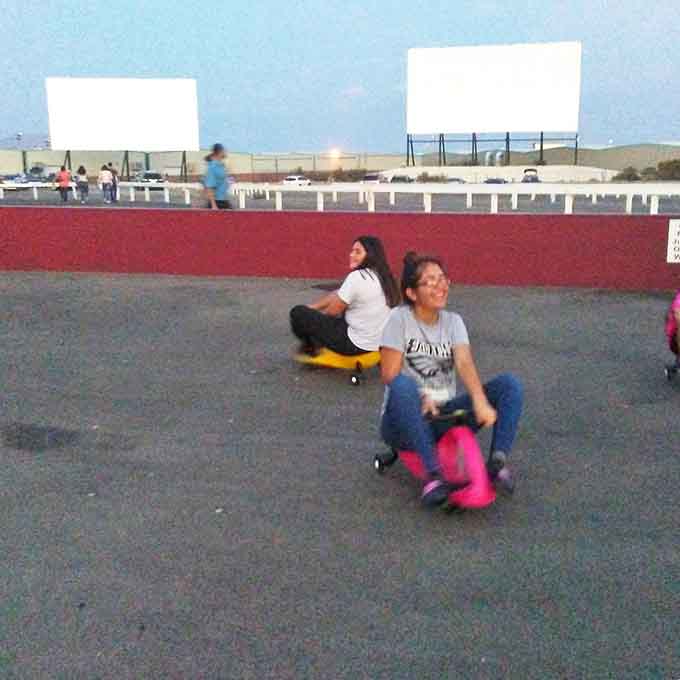 Teens cruise the lot on makeshift rides, creating their own entertainment before the main attraction. Youth finds a way, even at retro venues.