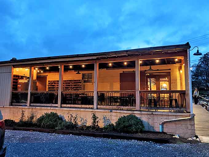 Twilight transforms this riverside porch into a glowing sanctuary where string lights and good company make even ordinary conversations feel momentous.