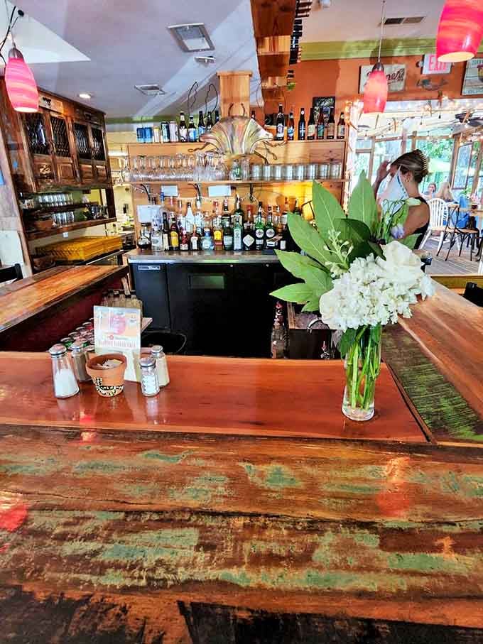 The bar area combines rustic charm with floral elegance. Where coastal cocktails are crafted while you contemplate ordering absolutely everything on the menu.