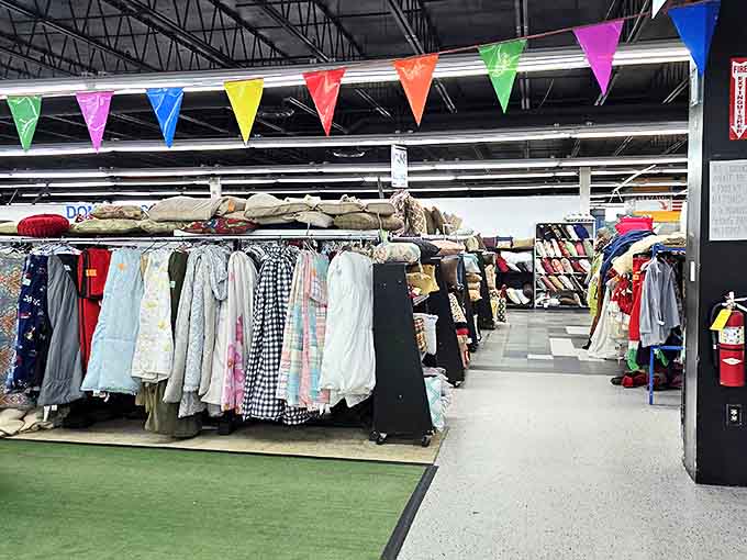 Colorful pennants flutter overhead like a permanent celebration of savings. The clothing racks below stand ready for your treasure-hunting expedition.