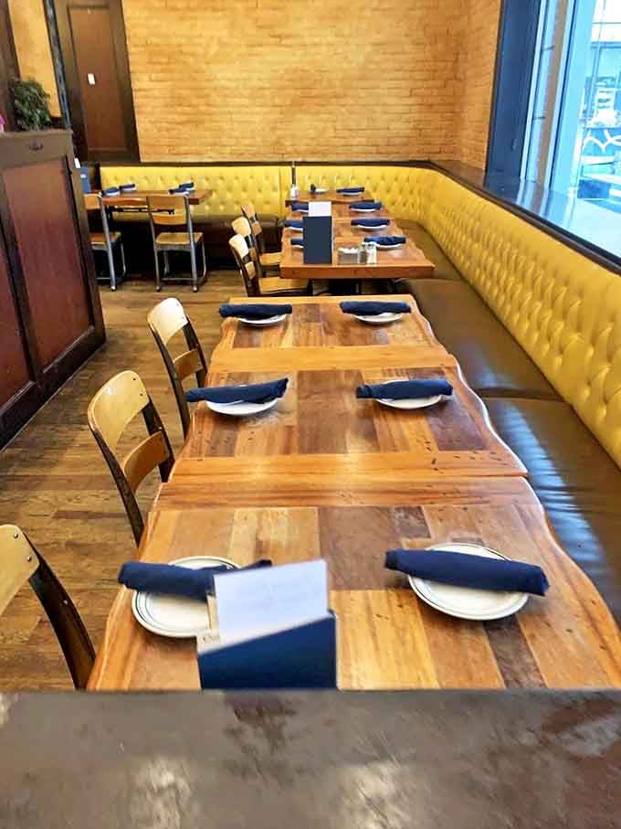Rustic wooden tables paired with mustard-yellow booths create a dining space that's both sophisticated and comfortable, like your favorite cardigan.