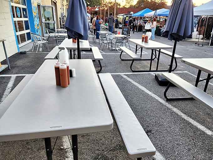 Outdoor seating where sauce bottles stand guard like delicious sentinels, ready to enhance your already perfect barbecue experience.