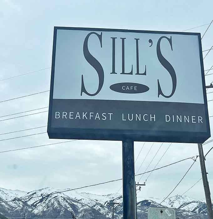 The roadside sign stands against a backdrop of snow-capped mountains, a beacon of hope for hungry travelers and locals alike.