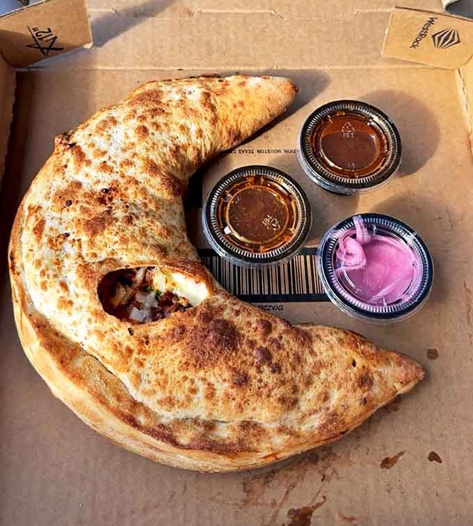 The calzone curves like a crescent moon, stuffed with treasures and accompanied by dipping sauces &ndash; a handheld feast of epic proportions.