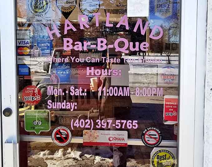 Hours of operation proudly displayed alongside a collection of accolades. "Where You Can Taste The Smoke" isn't just a tagline&mdash;it's a promise.