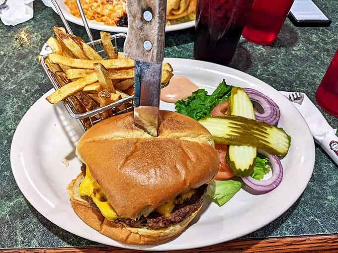 A burger stabbed dramatically with a knife, surrounded by crispy fries—diner theater at its finest, no reservations required.