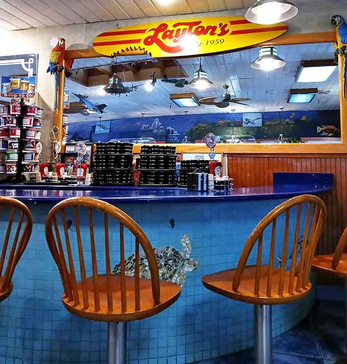 Counter seating beneath a vintage surfboard &ndash; because nothing says "coastal breakfast joint" quite like ocean-themed d&eacute;cor and blue countertops.