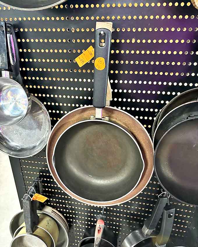 Kitchen tools hanging like culinary medals of honor. That cast iron pan has probably cooked more delicious meals than most celebrity chefs.