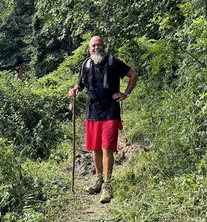 A hiker navigates the narrow shoreline path, proving that sometimes the most rewarding routes are the ones barely wide enough for your feet.