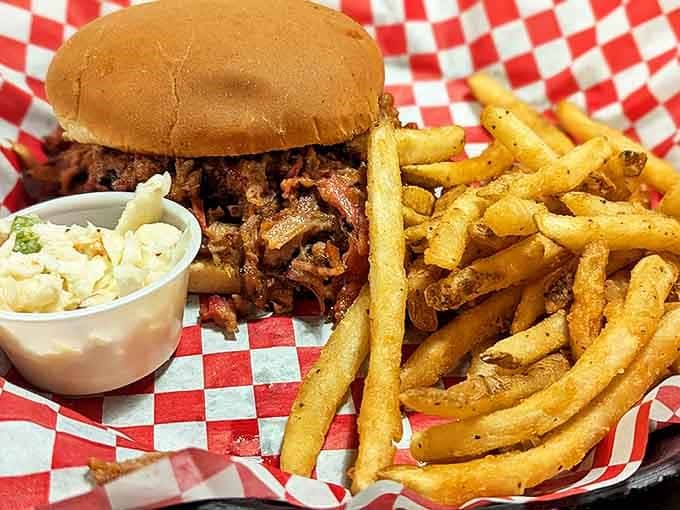 Pulled pork perfection on a bun. This sandwich, with its heap of smoky meat and golden fries, is what barbecue dreams are made of.