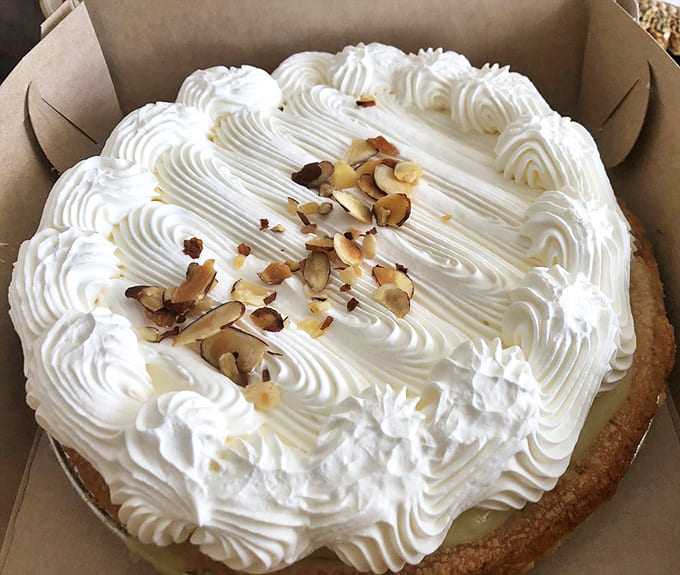 The banana cream pie wears its crown of whipped cream and almond slivers like royalty. Bow down to dessert perfection.