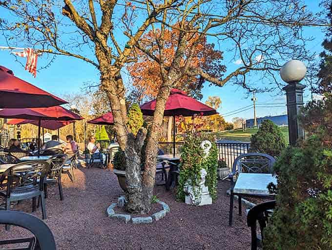 Outdoor dining under red umbrellas and dappled sunlight &ndash; nature's perfect lighting for both food and conversation.