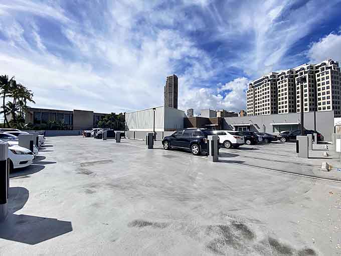 Paradise parking with urban views. The concrete lot might not be scenic, but it's the gateway to affordable retail therapy under brilliant Hawaiian skies.
