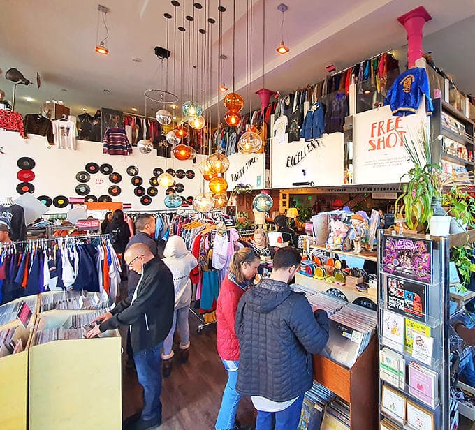 Treasure hunters in their natural habitat, flipping through vinyl while colorful pendant lights create the perfect ambiance for discovery.